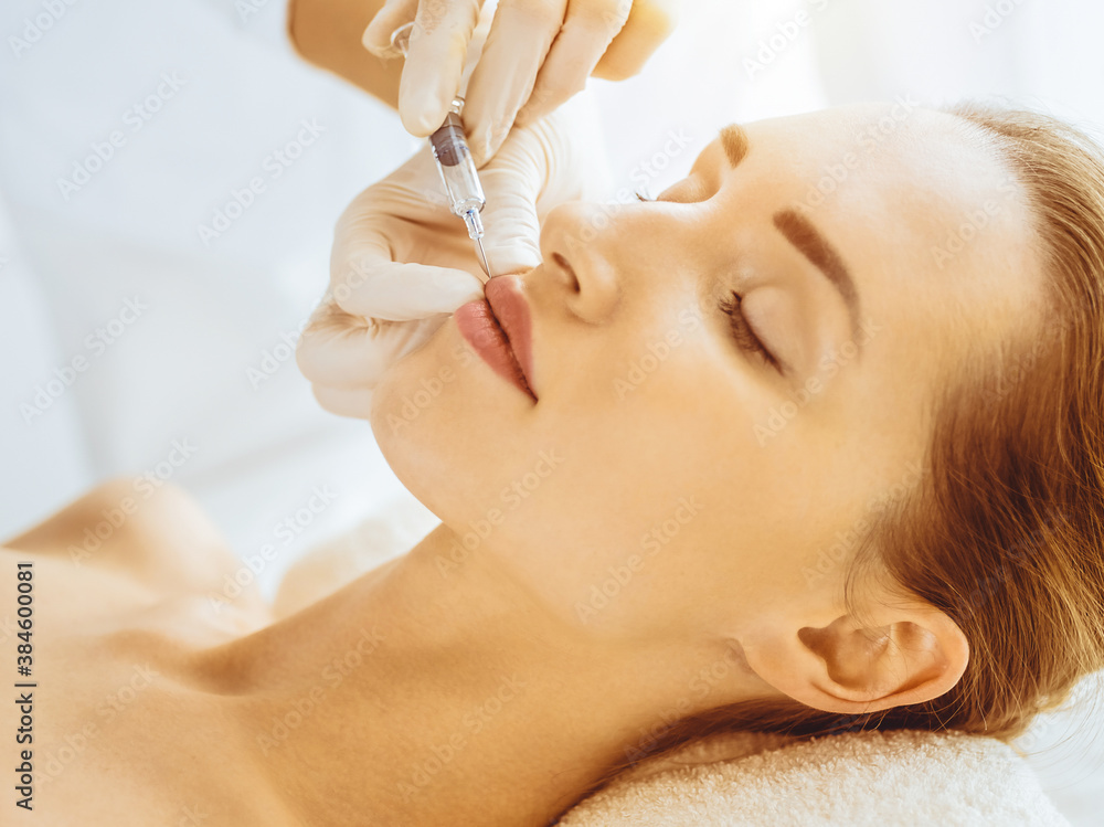 Beautiful woman receiving beauty injections with closed eyes in sunny ...