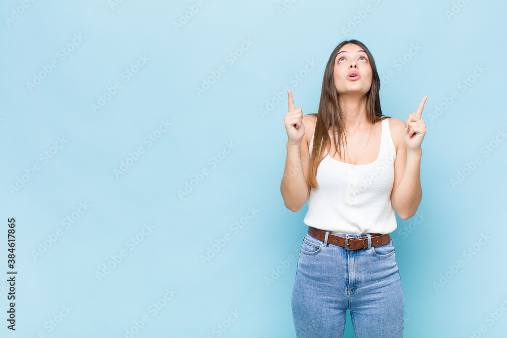 youn pretty woman feeling awed and open mouthed pointing upwards with a ...