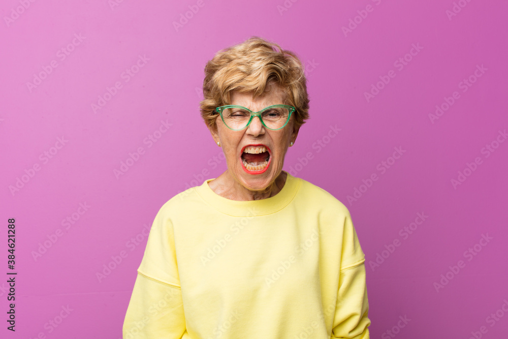 old pretty woman shouting aggressively, looking very angry, frustrated ...