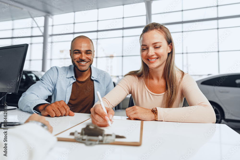 Beautiful young couple signs documents at car dealership showroom Stock ...