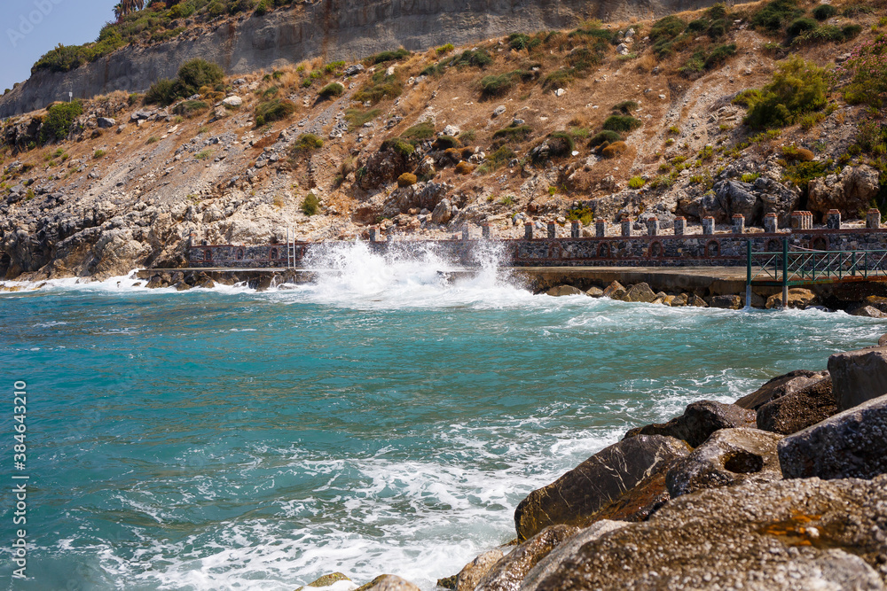 Sea water beats against rocky rocks and makes waves with foam, rugged ...