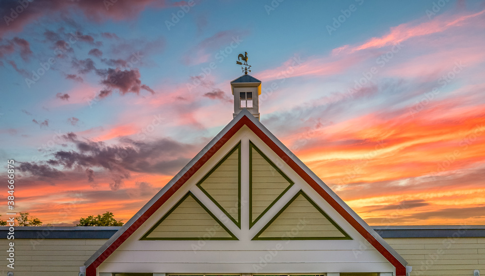 New gable roof with weather vane and dramatic sunset background on a ...
