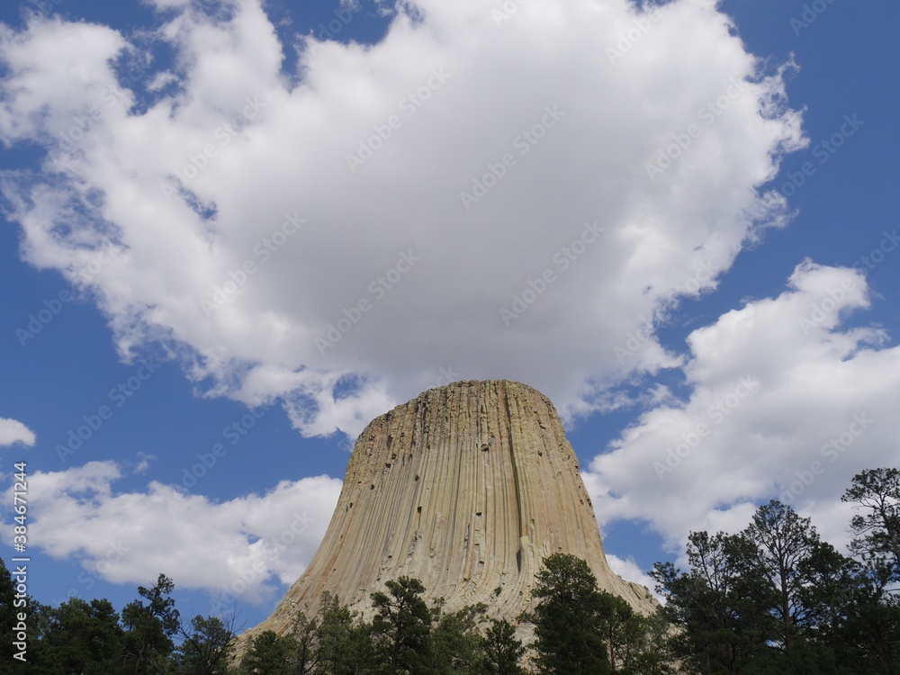 Upward shot of the Devils Tower with breathtaking clouds in the skies ...