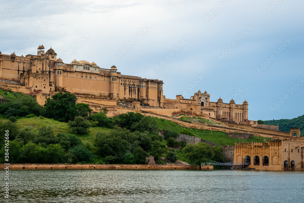 Intricately carved gateway Amer Fort Palace with maota lake and clouds ...