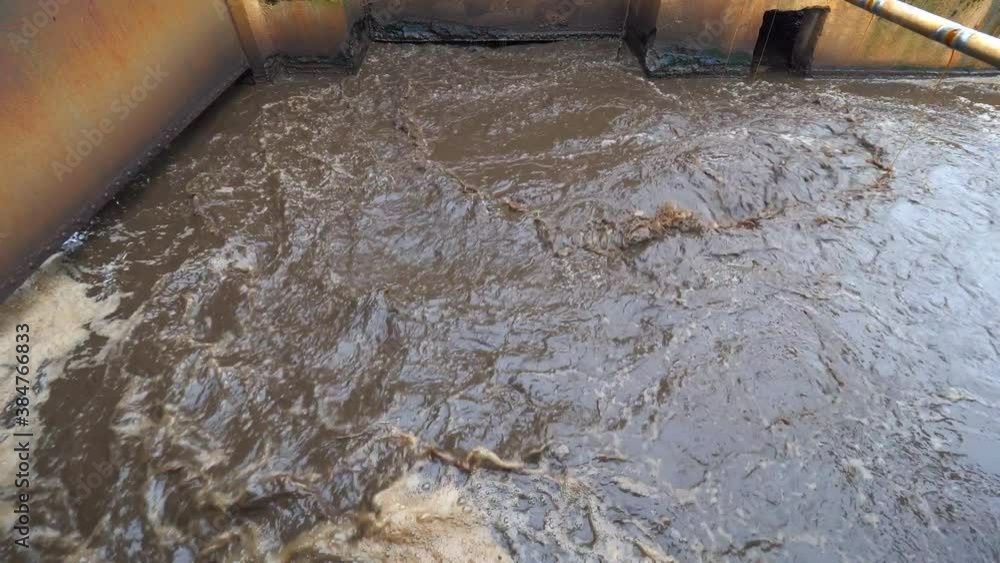 Thick sludge mixture in channel of wastewater treatment plant. Tanks ...