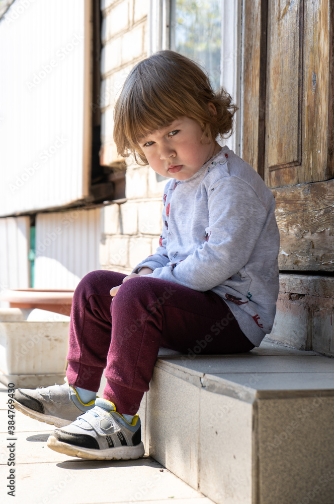 Little three years old boy sitting on stairs. Cute boy with long curly ...