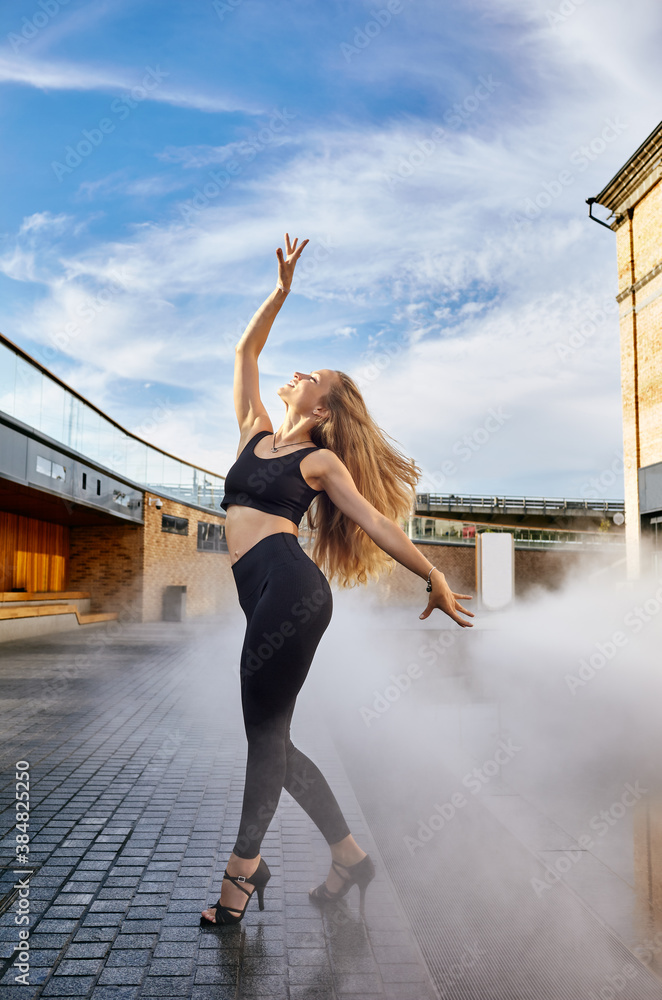 Beautiful woman dancer with long blond hair posing on city street ...