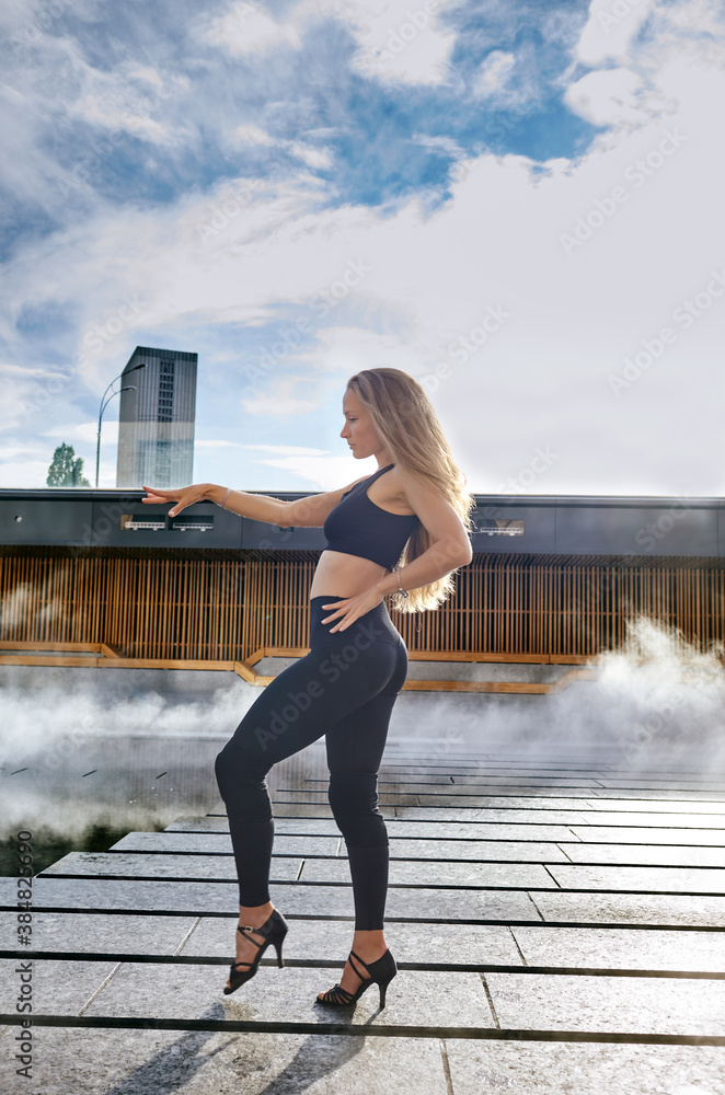 Beautiful woman dancer with long blond hair posing on city street ...