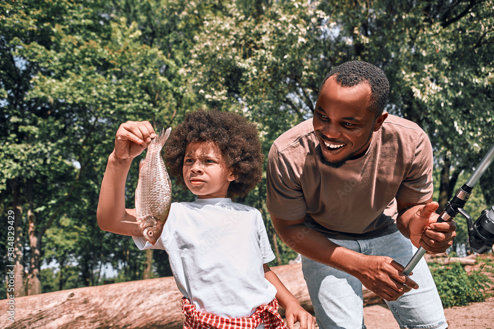 Curly boy holding a fish he just caught with his dad Stock Photo ...