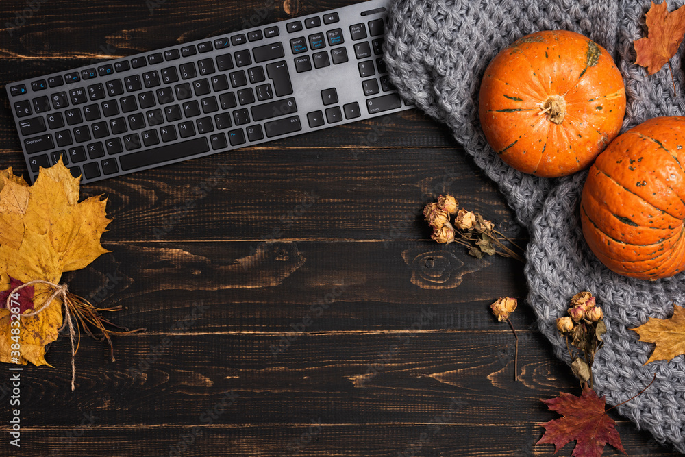 Laptop on workspace with yellow and red maple leaves and pumpkin on ...