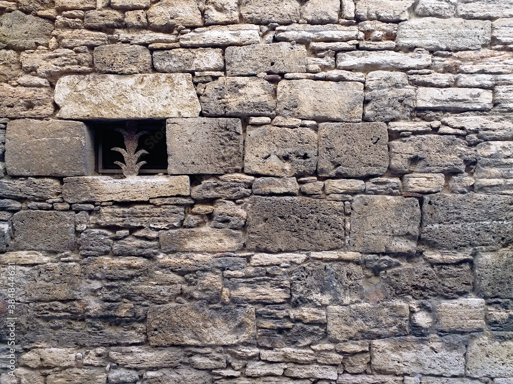 Small window in the medieval stone wall. Old historic natural stone ...