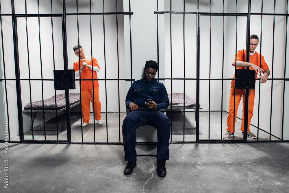 A strong black prison guard guards the cells with prisoners in the ...