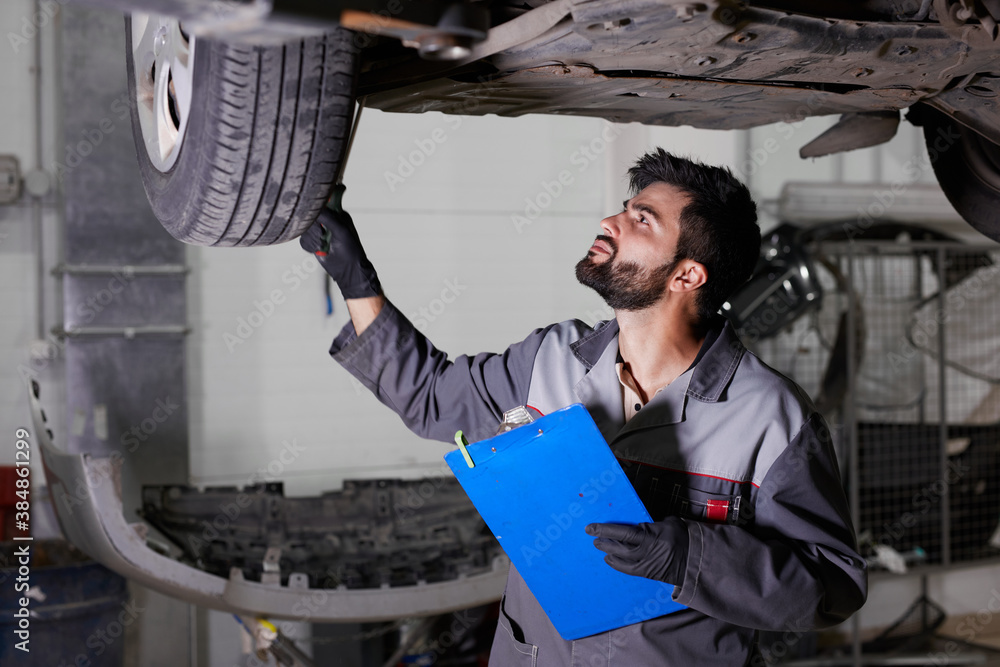 caucasian auto mechanic writing job checklist to clipboard to estimate ...