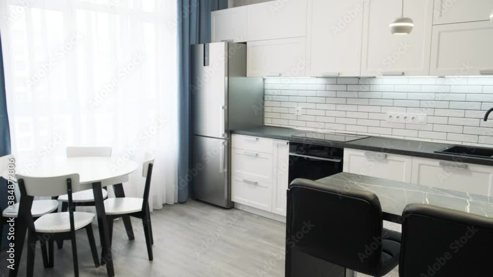 Steadycam shows elegant modern kitchen with white walls. Light interior ...