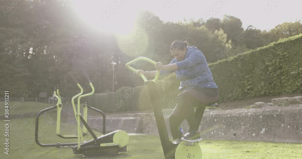 Plus size female exercising at outdoors gym on bicycle, Obese ...