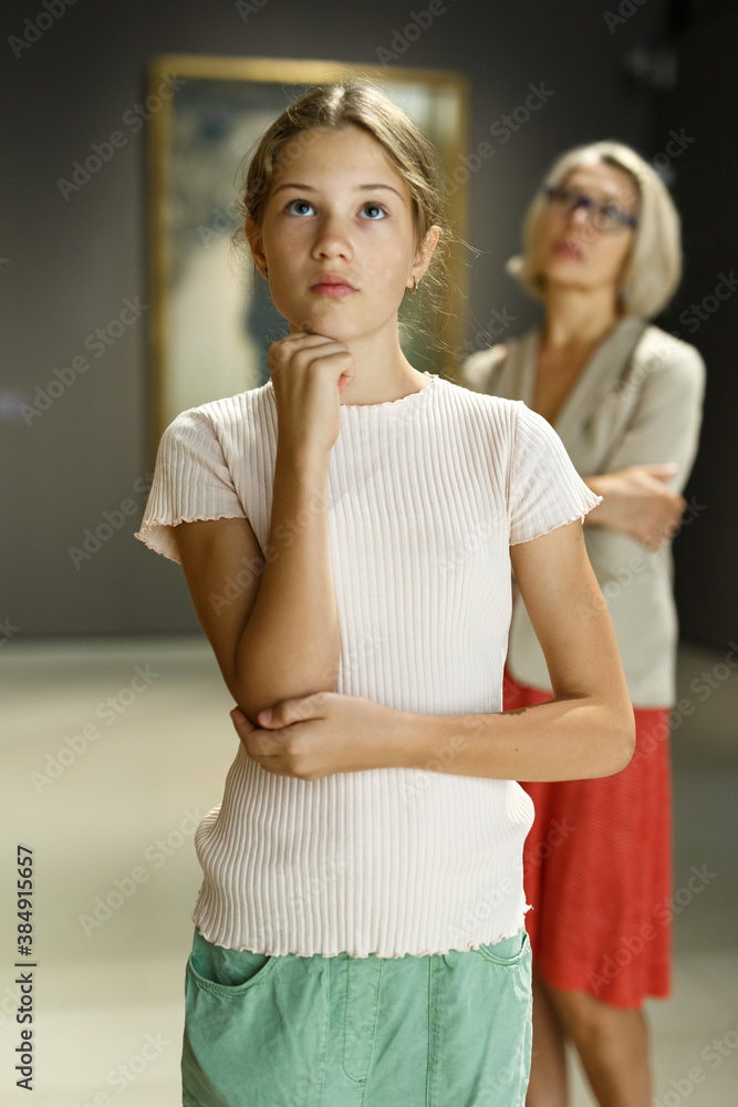 Positive tween girl observing with interest exhibition in art gallery ...