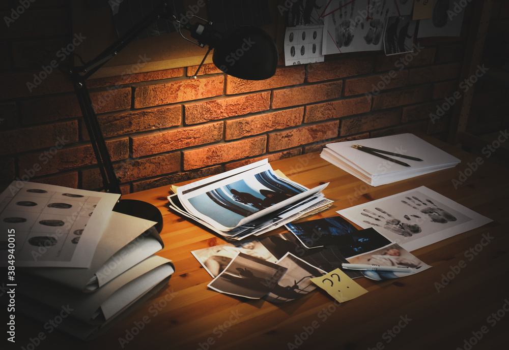 Detective workplace with documents, fingerprints and crime scene photos ...