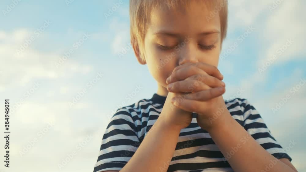 boy prays against a blue sky. child close-up concept faith religion and ...