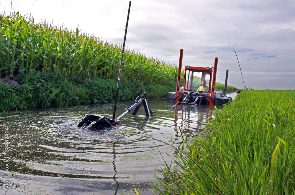 Mini floating suction cutter dredger in operation . The cutter arm cuts ...