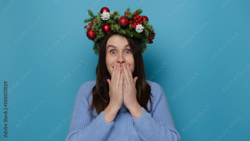 Happy shocked woman in traditional Christmas wreath, keeps palm on ...
