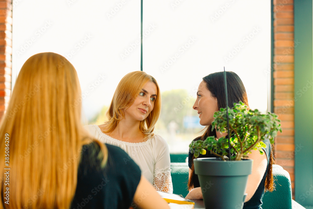 Girls gossip. Three best friends speaking in cafe. Smiling females ...