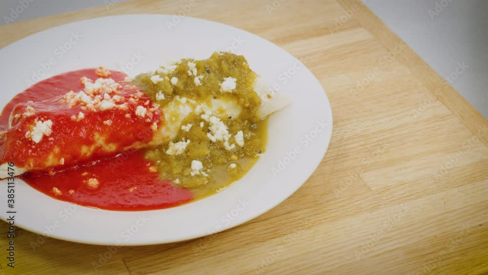Panning over a burrito smothered in red and green chile sauce. The ...