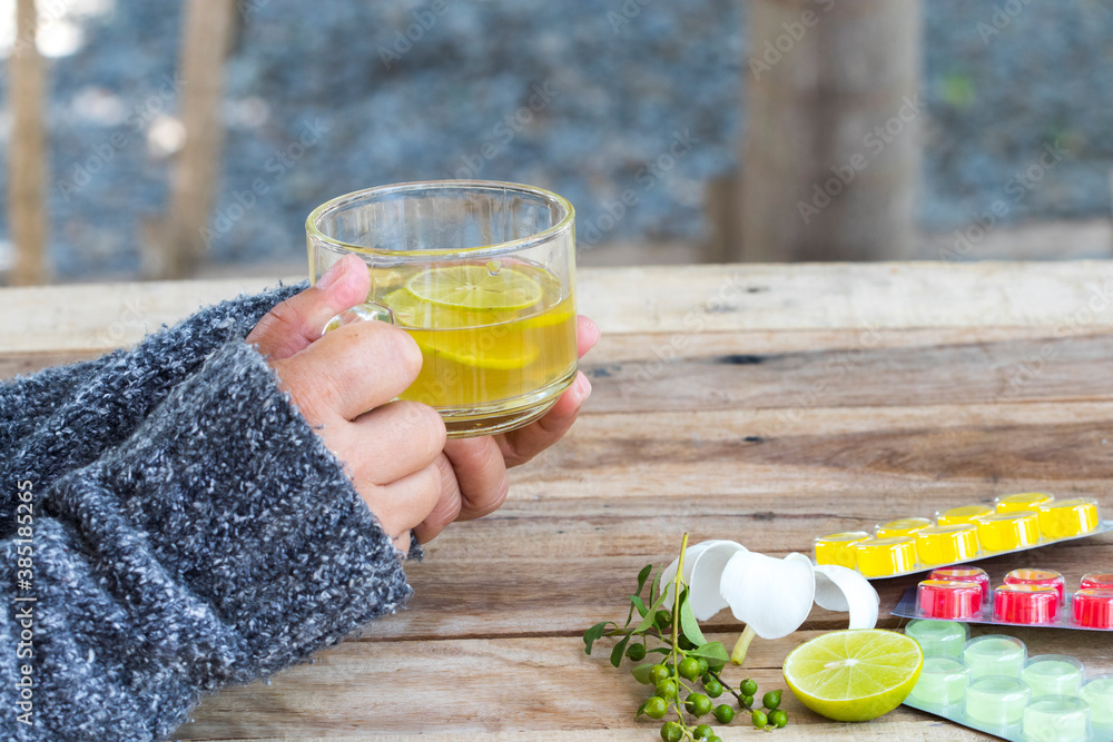 hand of woman holding herbal healthy drinks hot honey lemon and lozenge ...