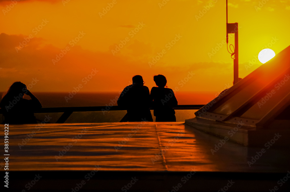 Silhouette of people at railing on luxury cruiseship or cruise ship ...