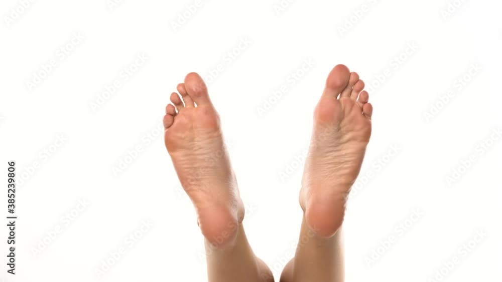 a woman slowly moving and stretching her bare feet on a white ...