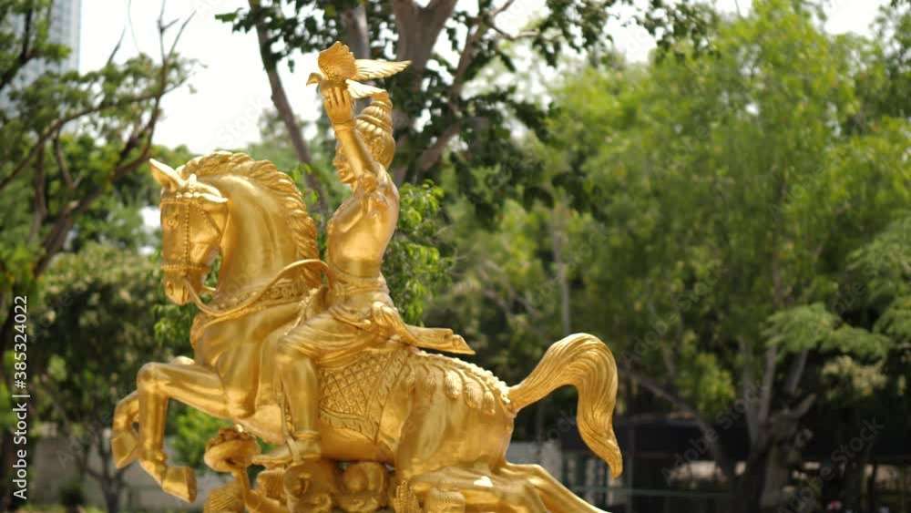 Golden statue in park of famous Asian man riding horse in traditional ...