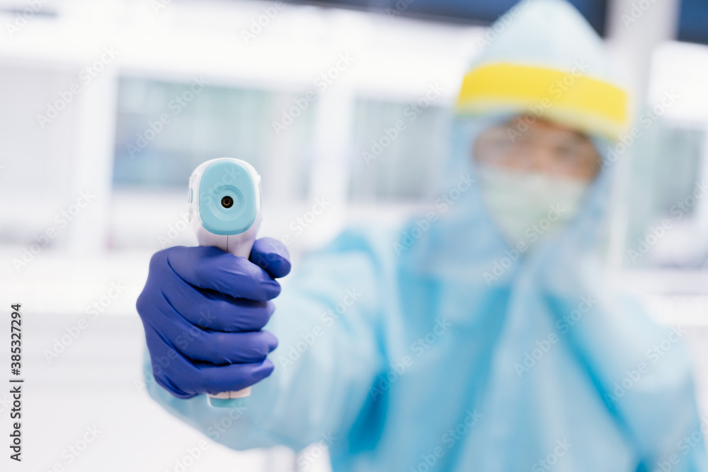 Close up of doctor wearing PPE suit uniform ready to use thermometer ...
