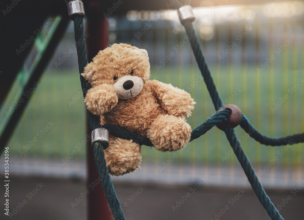 Lost teddy bear toy lying on rope frame at playground in gloomy day ...