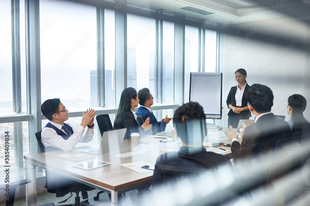 new asian team member making a self introduction during group meeting ...
