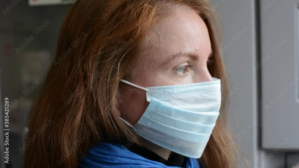 Portrait of a european redhead girl in disposable mask turns to the ...