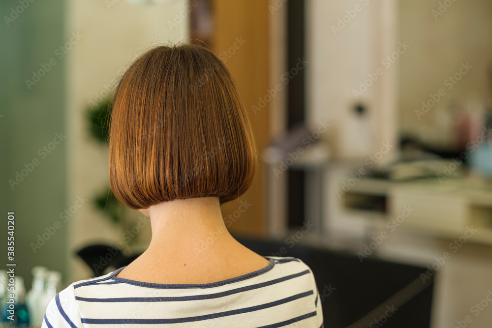 Young woman had her hair cut and styled in a beauty salon. She is ...