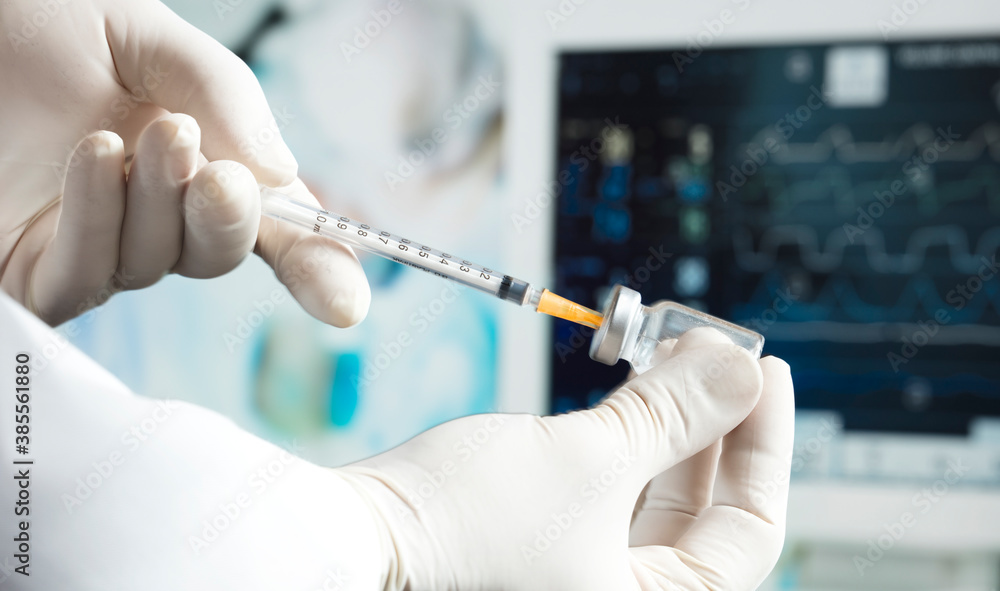 Syringe in the doctor's hand, (focus on orange needle cannula) hospital ...