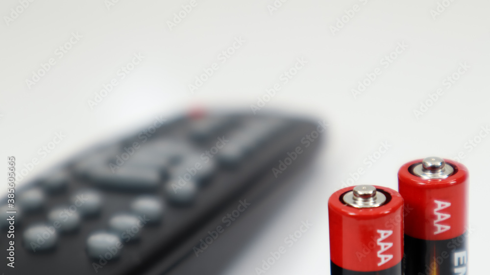 Black TV remote control with AAA alkaline batteries in red and white on ...