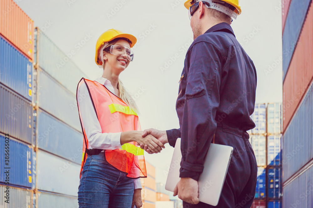 Engineer and worker handshake with blurred containers cargo background ...