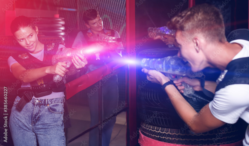 Group portrait of jolly emotional people with laser guns playing laser ...