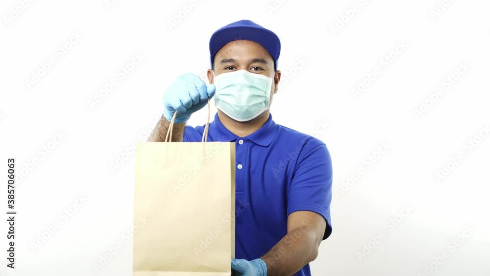Young asian delivery man in blue uniform wearing protection mask and ...