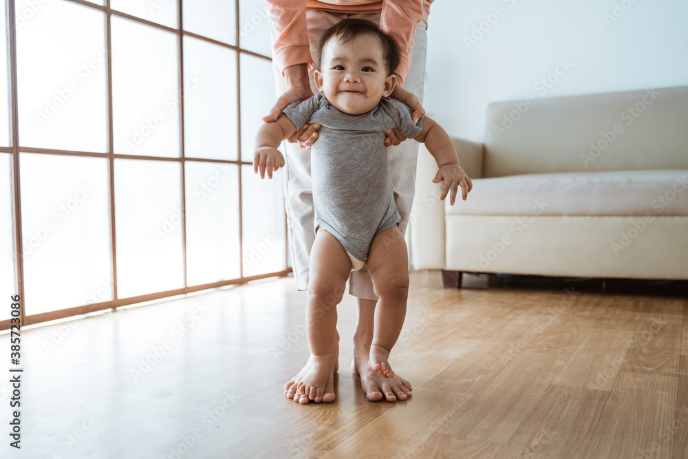 baby first step walking. mother help her baby to walk her first step at ...