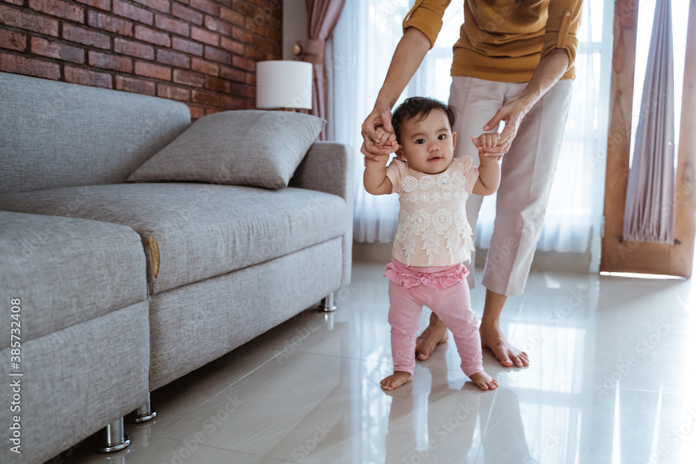 baby first step walking. mother help her baby to walk her first step at ...