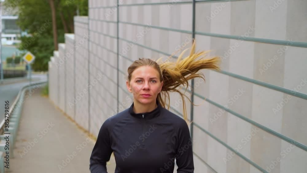 Young woman with ponytail wearing black sportswear running upwards near ...