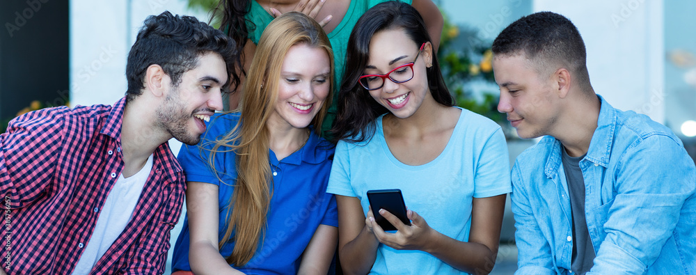 Female influencer with mobile phone and group of young adult friends ...