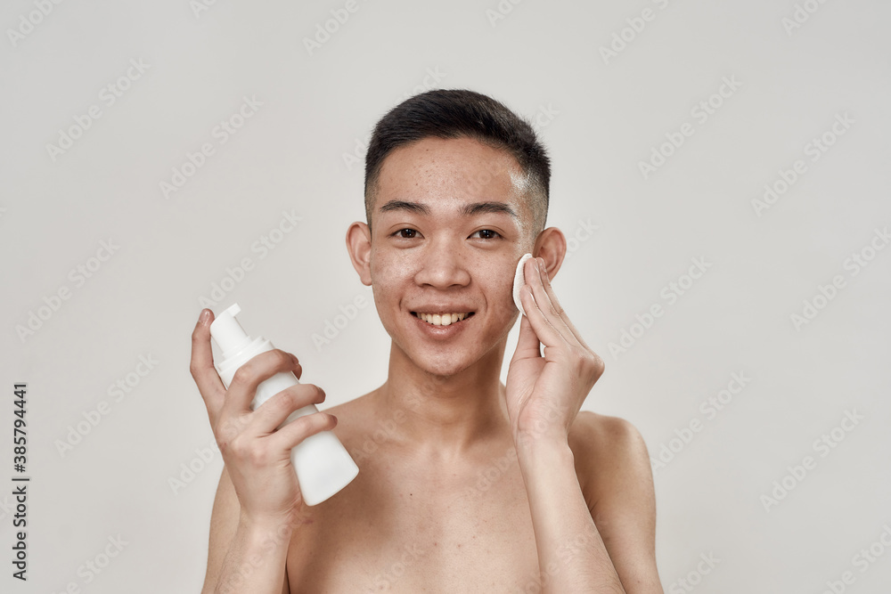 Portrait of shirtless young asian man with problematic skin cleaning ...
