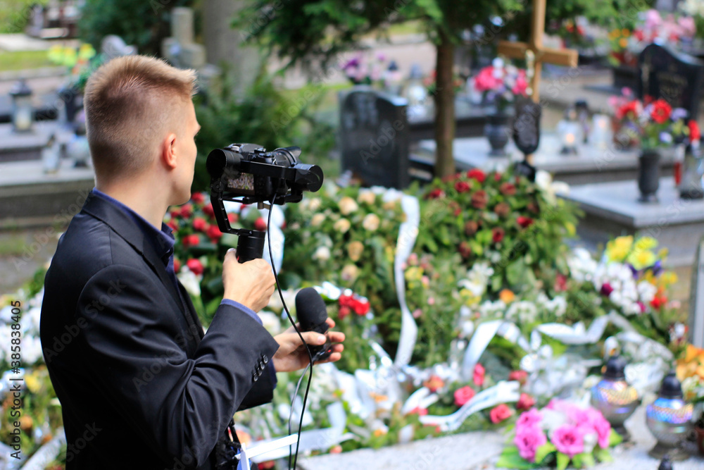 Foto de Elegant man in suit is recording grave with cross full of ...