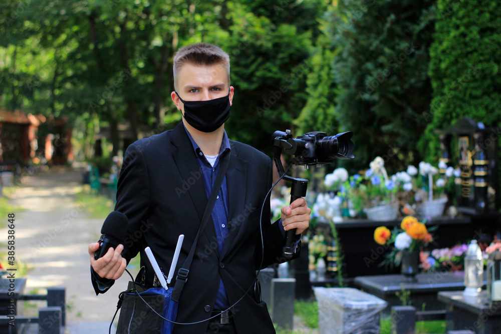 Elegant man in suit is recording grave with cross full of flowers ...