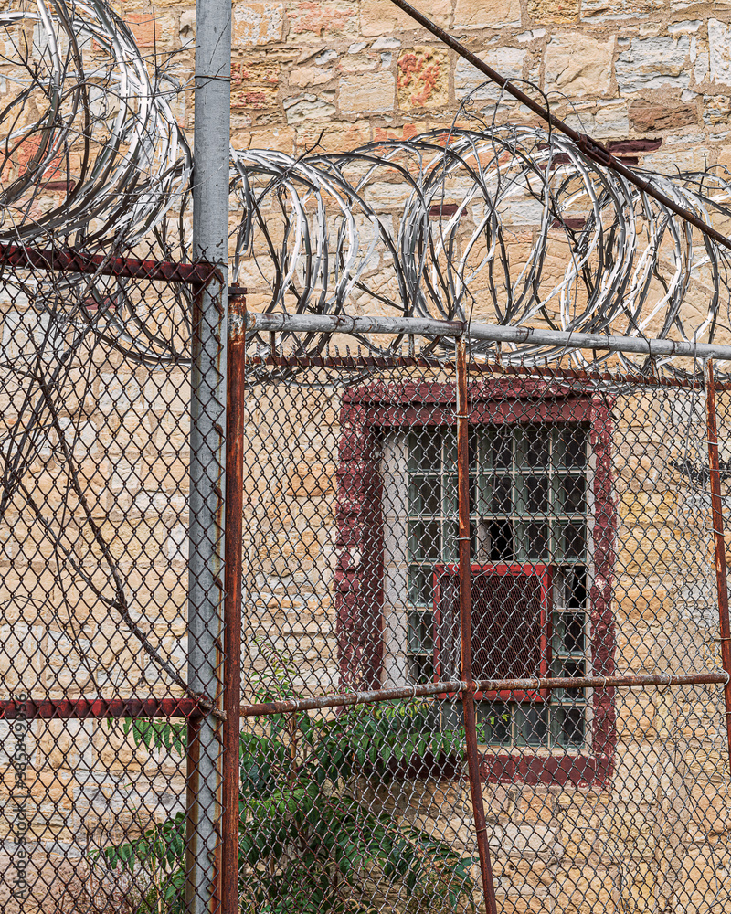 Barb wire on top of old cyclone fence positioned in front of block ...