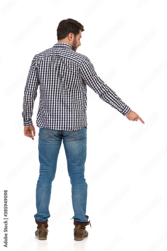 Casual Young Man In Boots, Jeans And Lumberjack Shirt Is Pointing Down ...