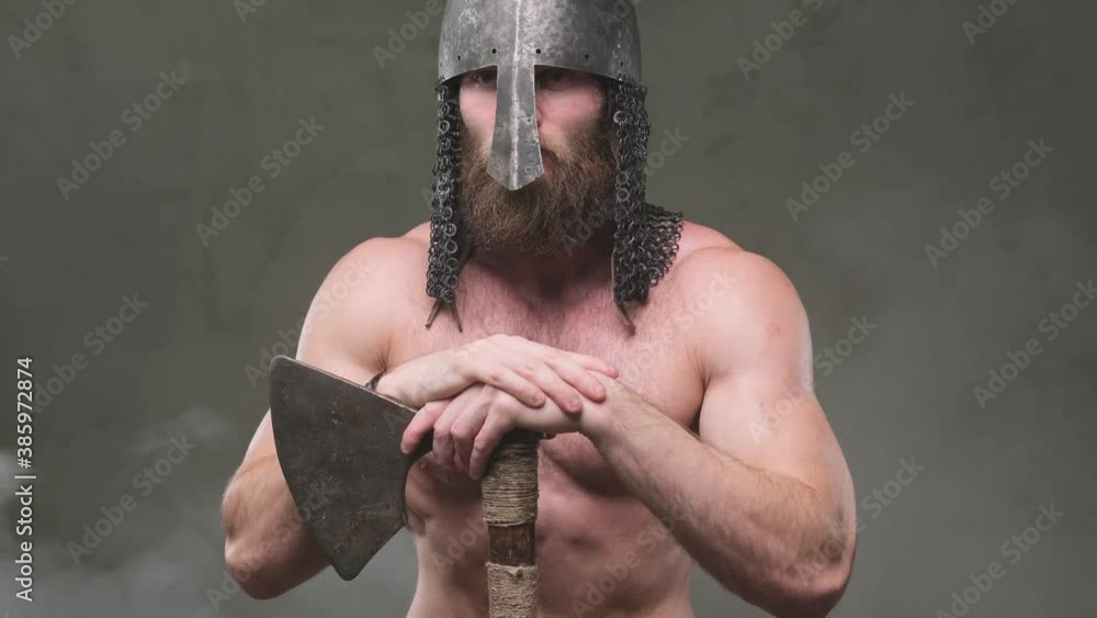 Stationary bearded and shirtless scandinavian warrior poses holding axe ...